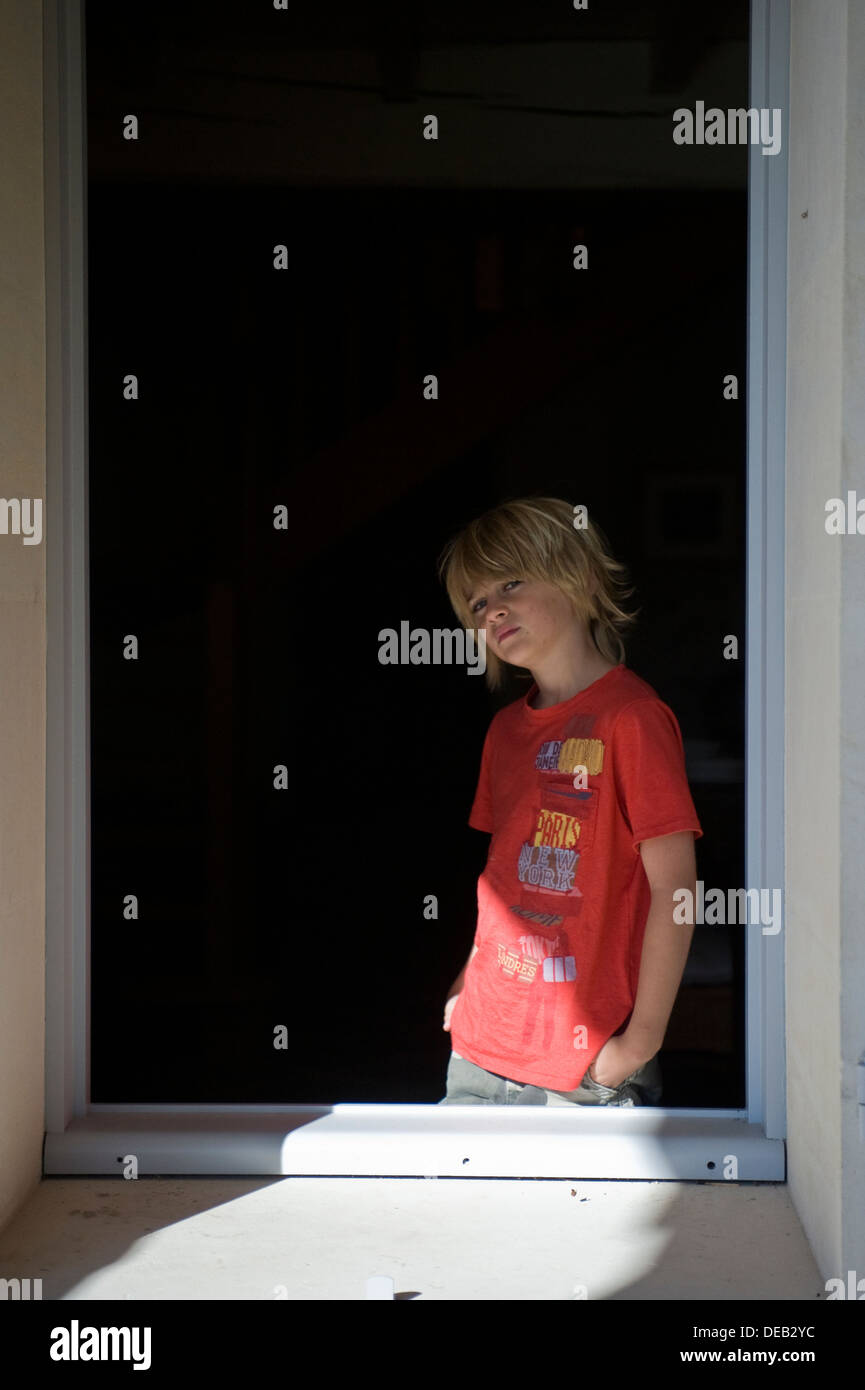 A moody blond boy looks out of a window Stock Photo - Alamy