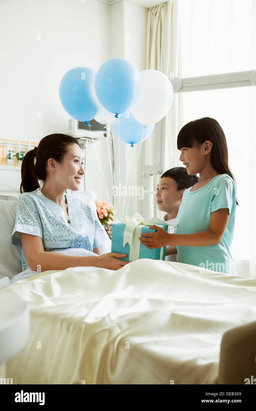 Girl and boy visiting their mother in the hospital, giving present and ...