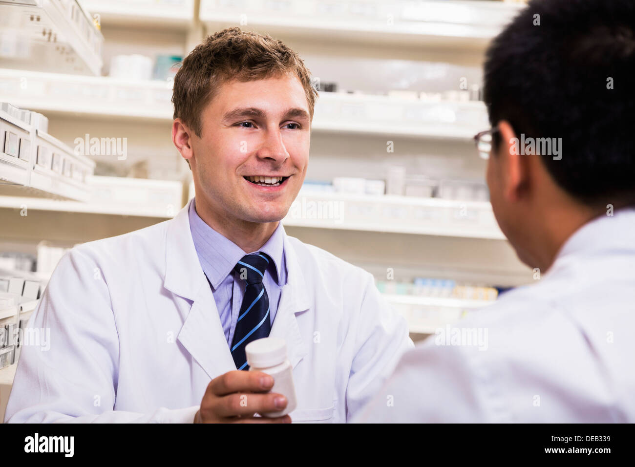 Smiling young pharmacist showing prescription medication to a customer ...