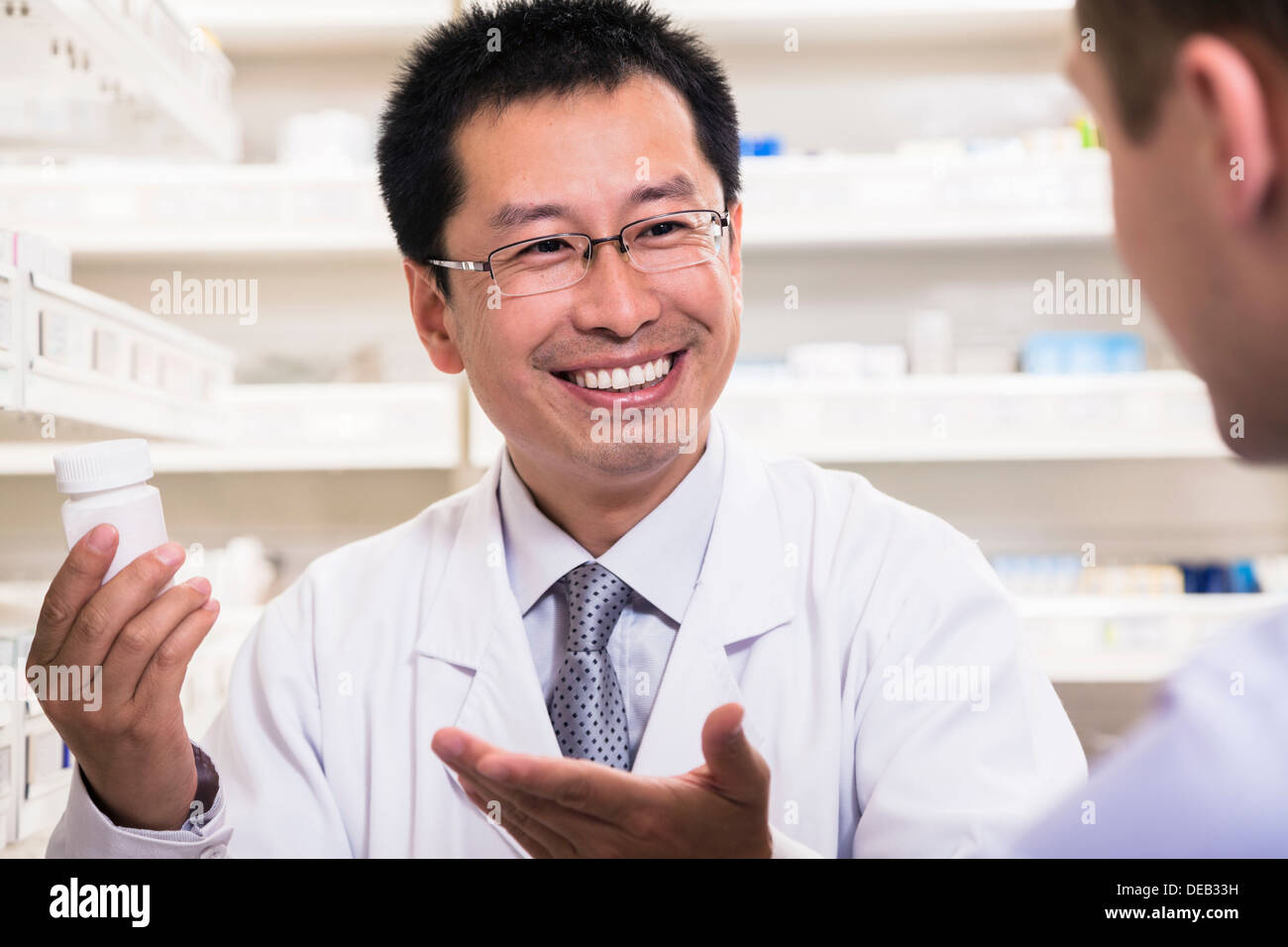 Smiling pharmacist showing prescription medication to a customer Stock ...
