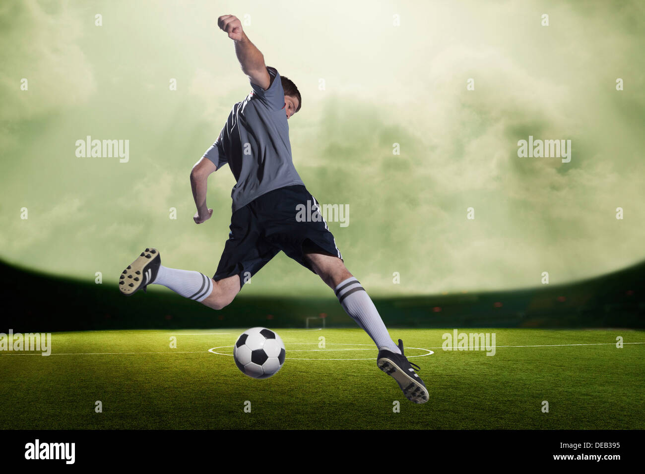 Soccer player kicking the ball in a stadium, green sky with clouds ...