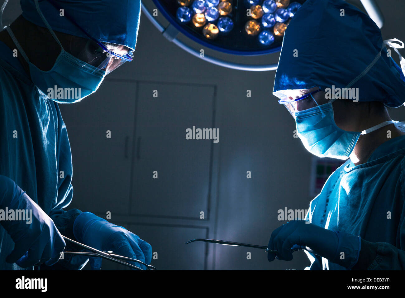 Two surgeons looking down and working at the operating table, dark ...