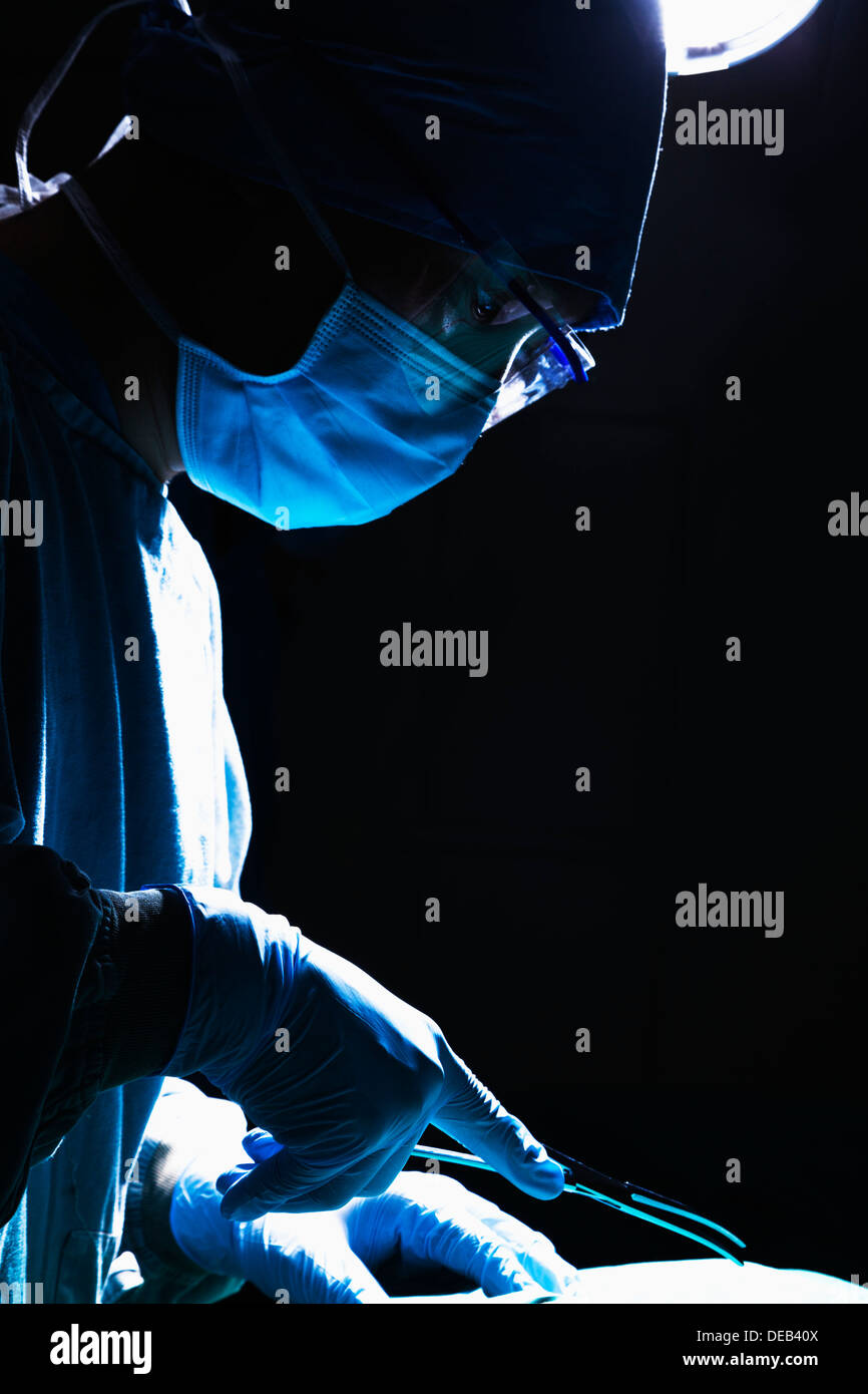 Surgeon looking down, concentrating, and holding surgical equipment in ...