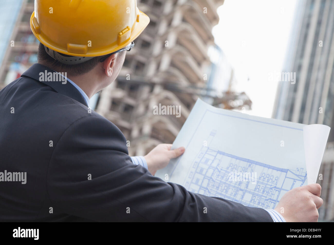 Architect on site looking at blueprints Stock Photo - Alamy