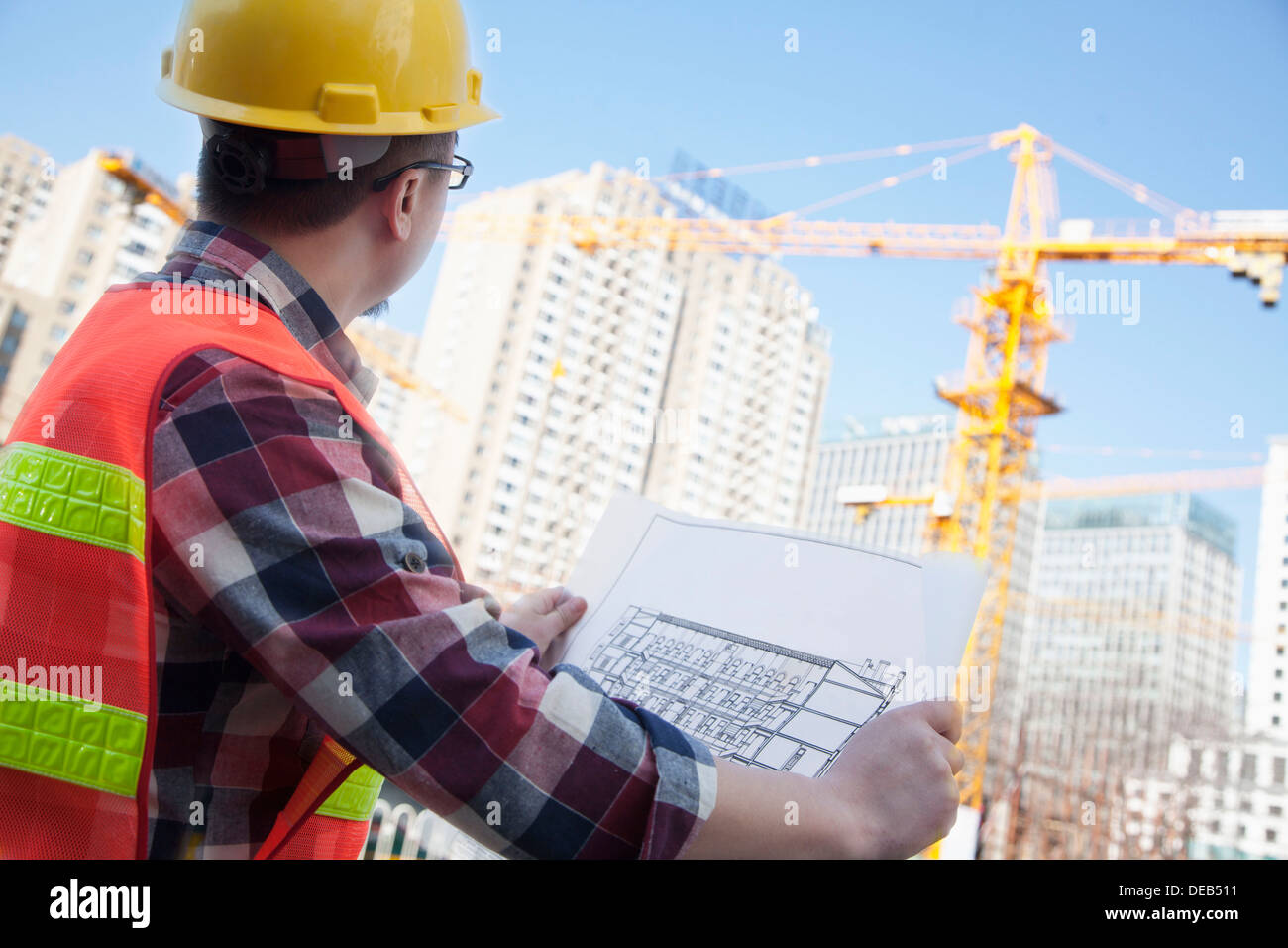 Architect looking at a blueprint outdoors at a construction site Stock ...