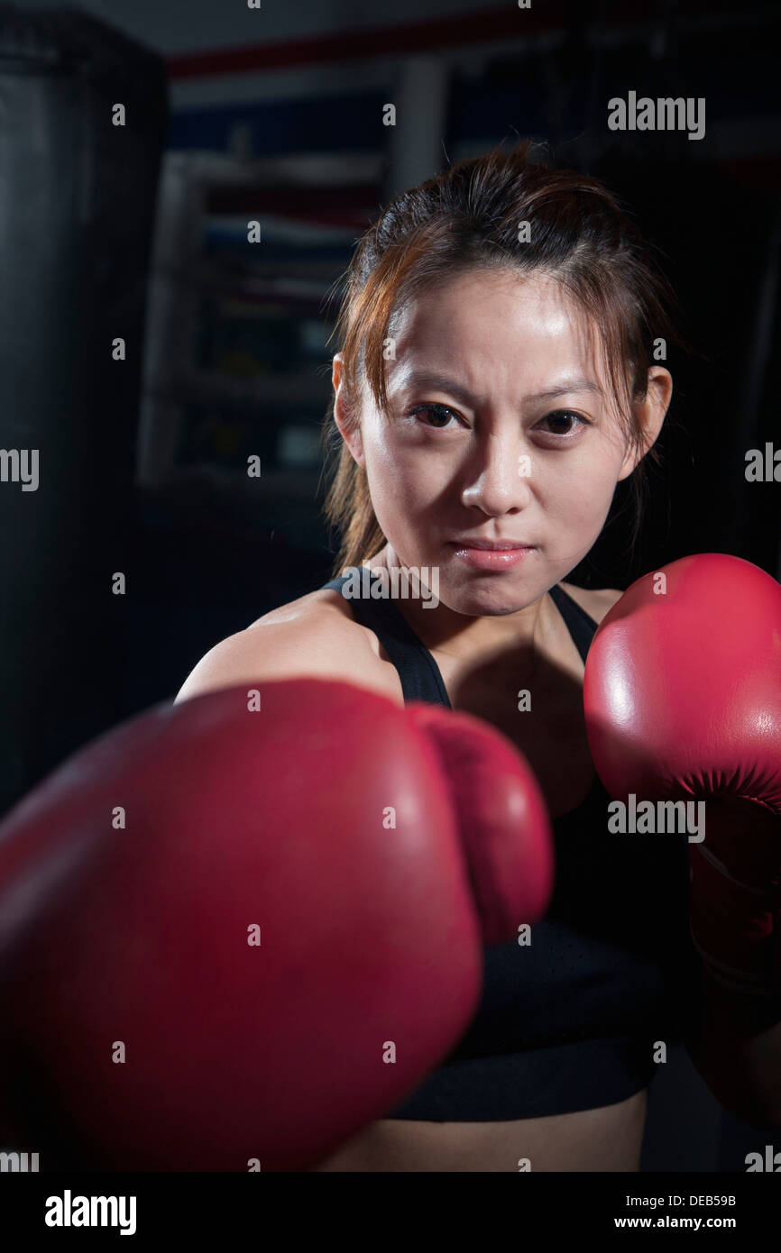 Portrait of determined female boxer in fighting stance looking at ...