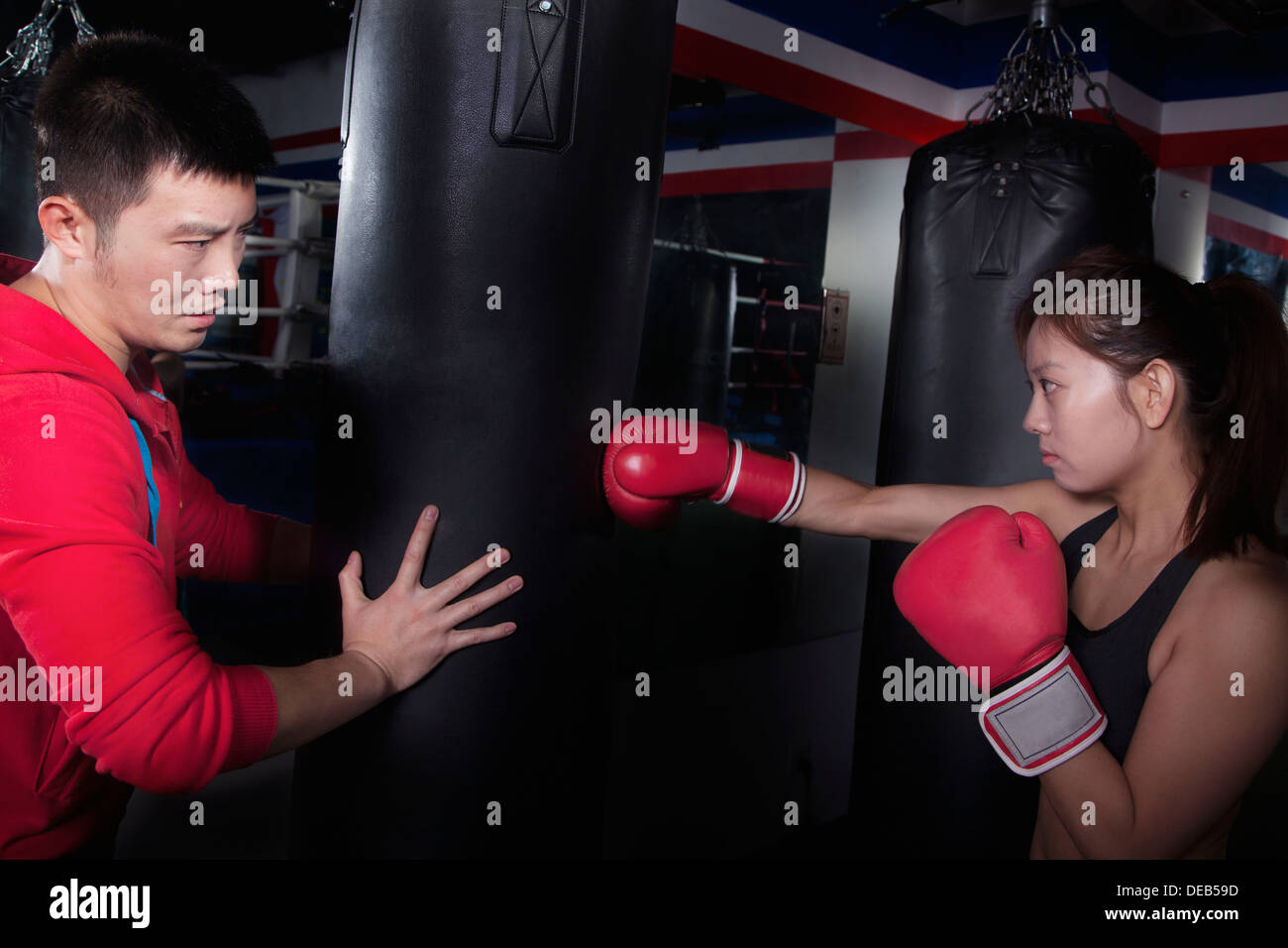 Boxing couch holding the punching bag and training a female student ...