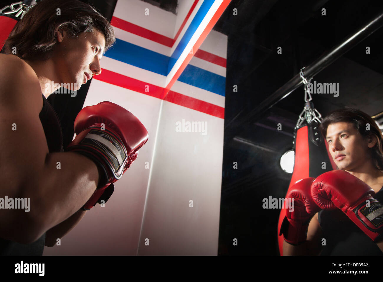 Confident boxer looking at himself in the mirror and working on his ...