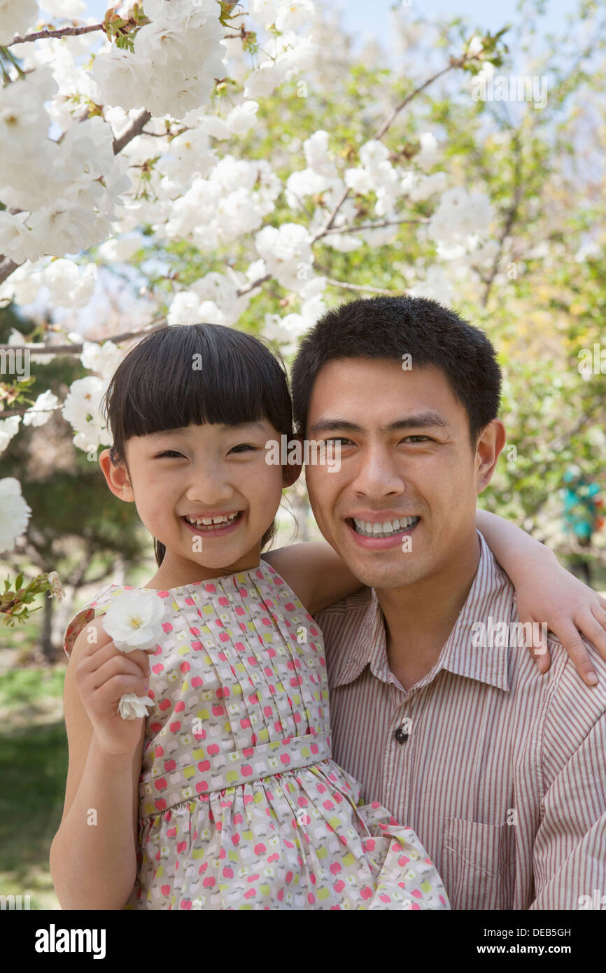 Smiling father and daughter enjoying the cherry blossoms on the tree in ...