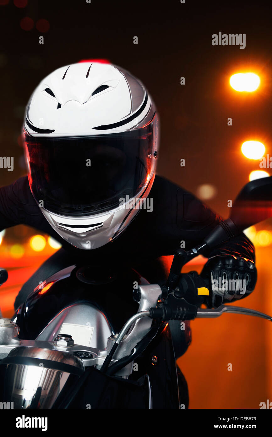 Young man riding a motorcycle at night through the streets of Beijing ...