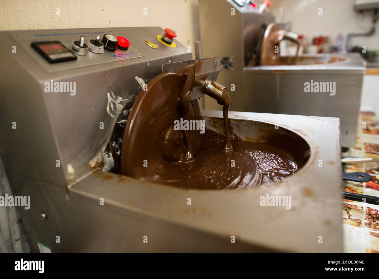 A chocolate moulding machine full of molten dark chocolate at an ...
