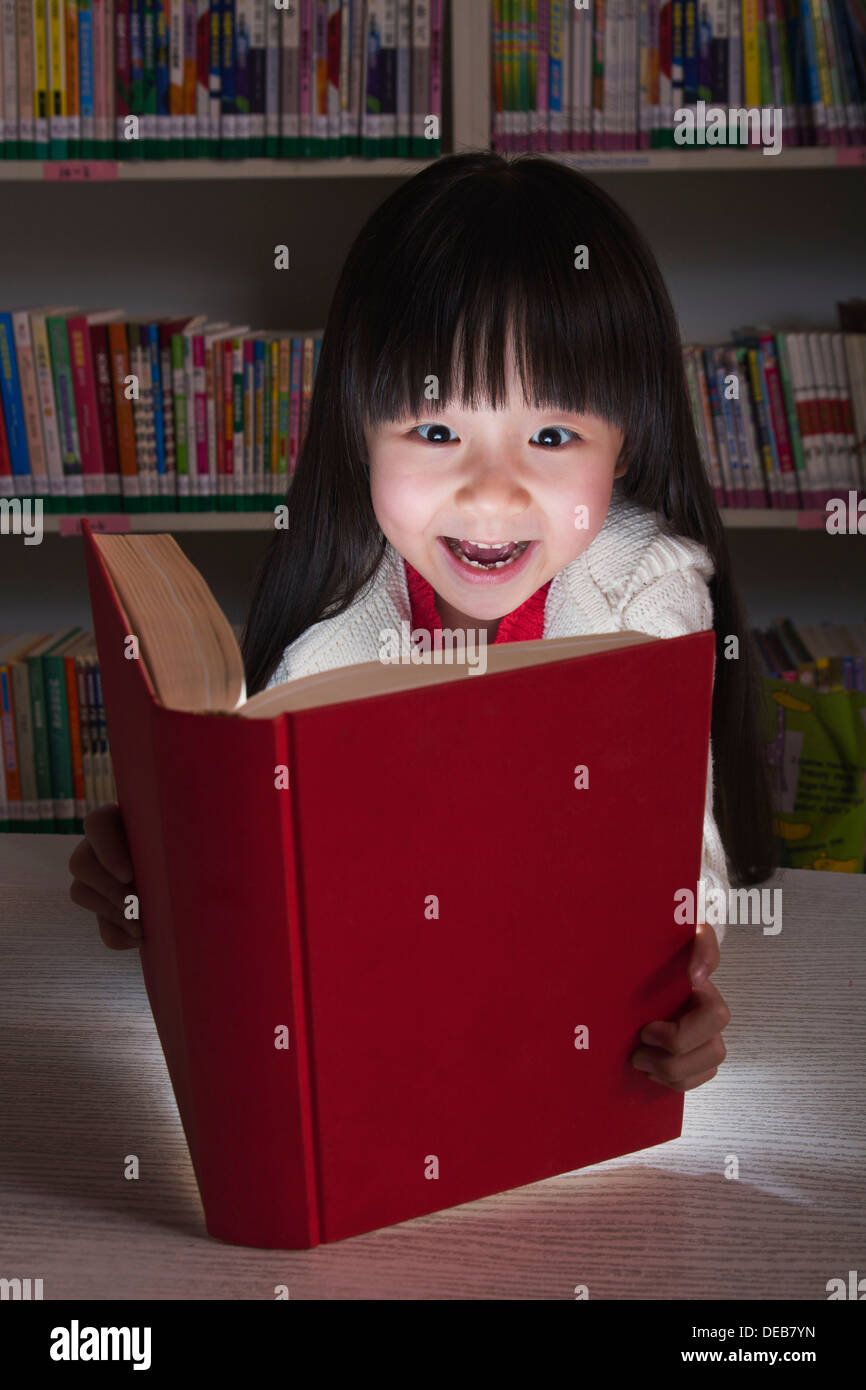 Girl Surprised By Glowing Book Stock Photo - Alamy