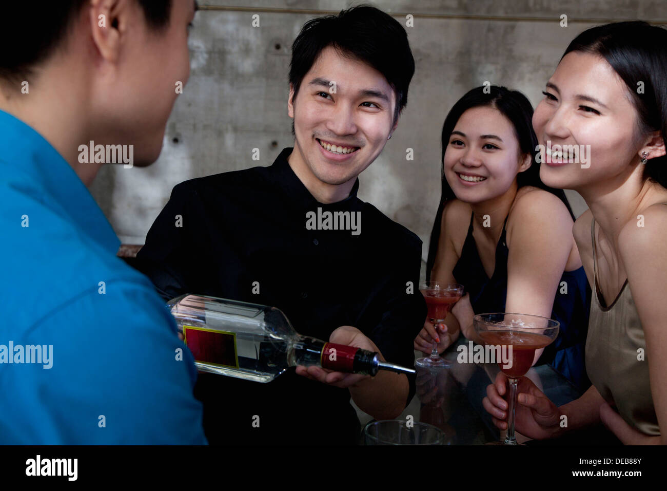 A young men bartender serving drinks to group of friends Stock Photo ...