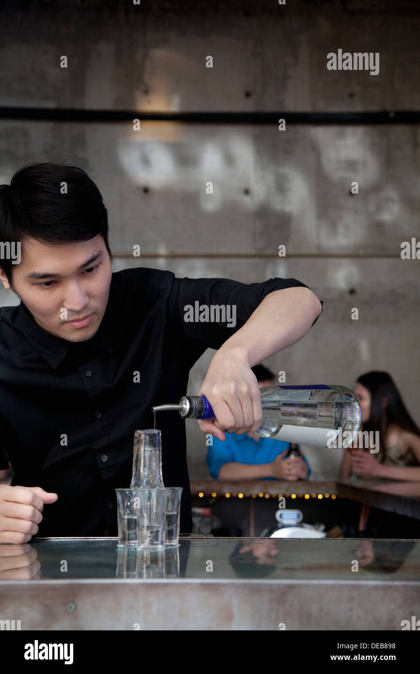 Bartender pouring liqueur on shot glass pyramid Stock Photo - Alamy