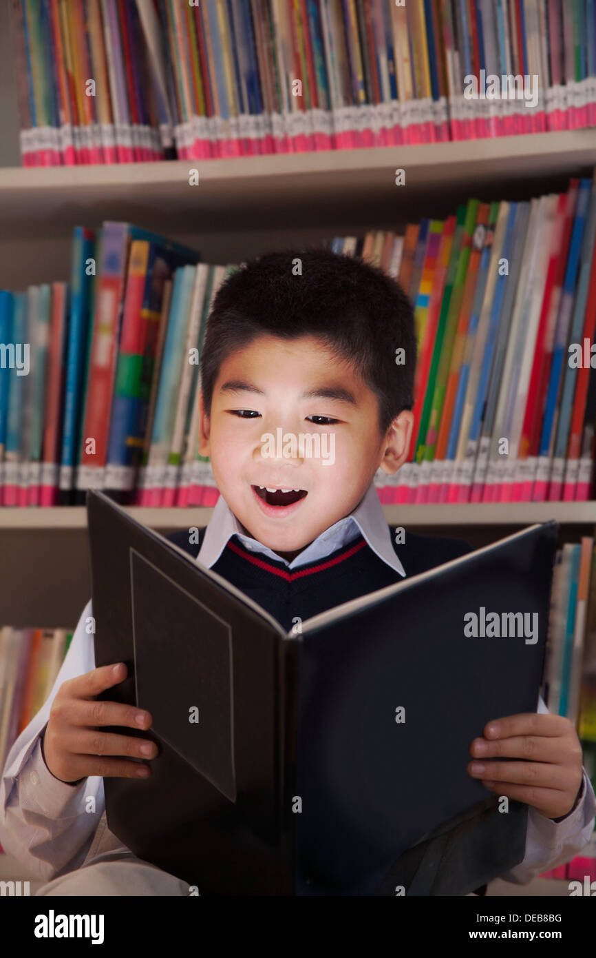 Schoolboy reading a book with her face lit up Stock Photo - Alamy