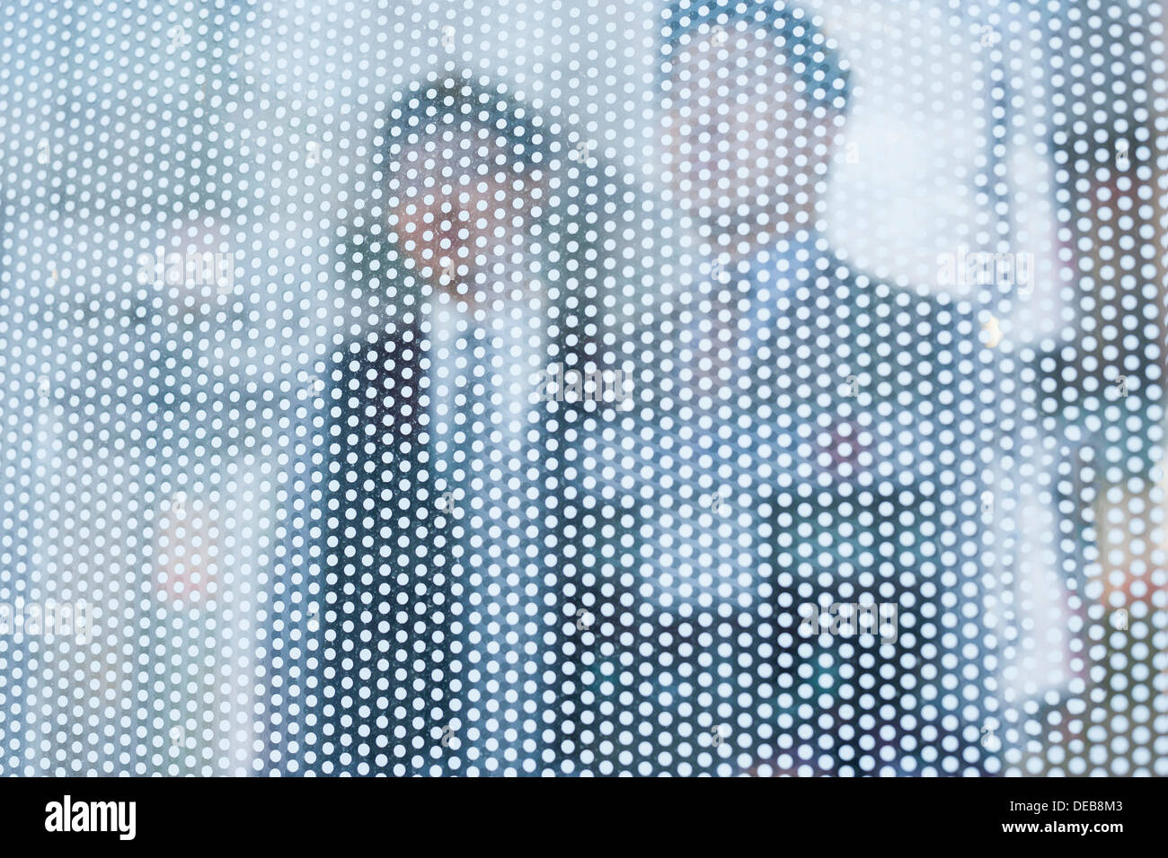 Two businessmen behind a glass wall looking out, unrecognizable faces ...