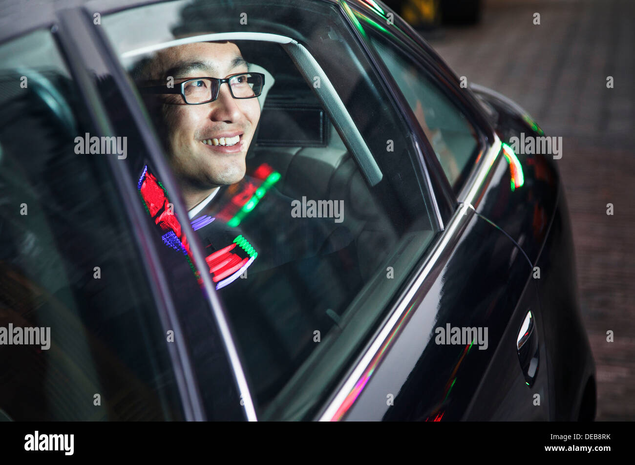 Smiling And Happy Businessman Looking Through Car Window At The Night