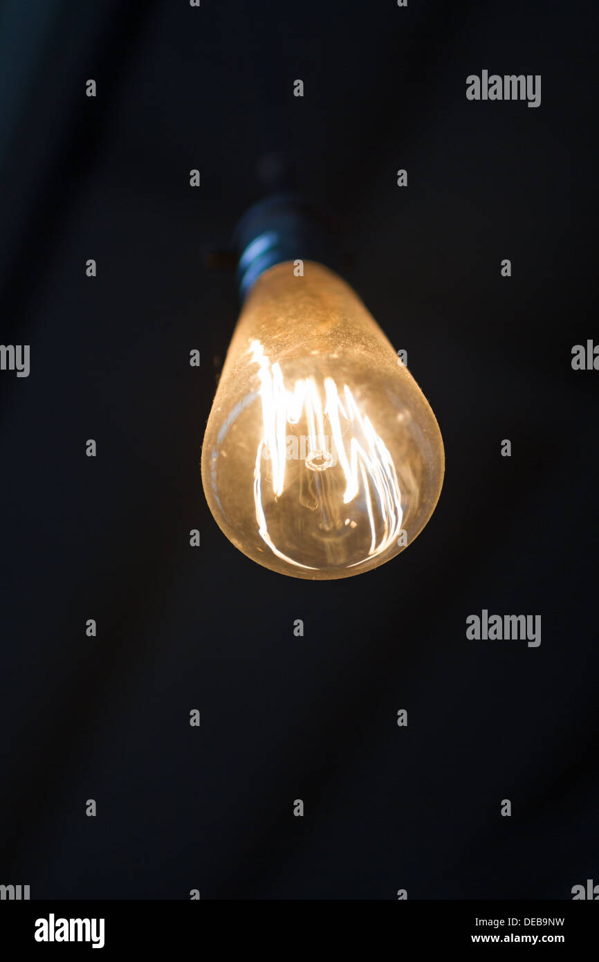 An illuminated antique-style Edison light bulb against a dark ...