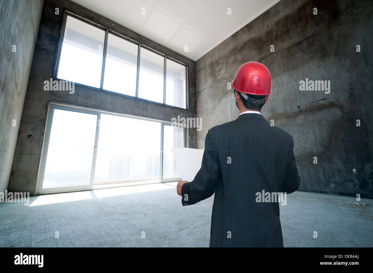 Rear view of architect looking comparing housing project with building ...
