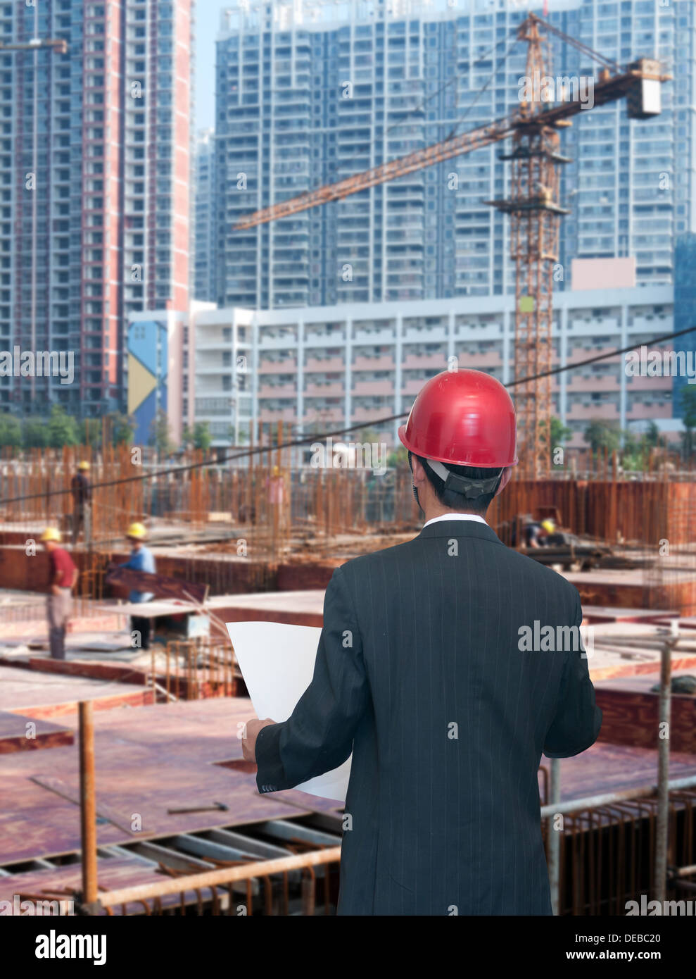 Rear view of architect looking comparing housing project with building ...