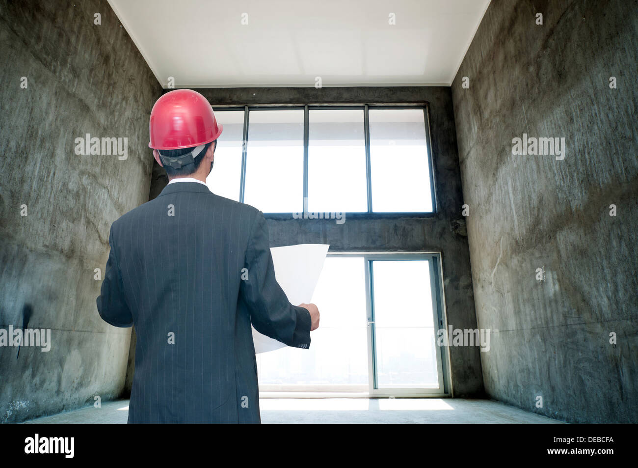 Rear view of architect looking comparing housing project with building ...