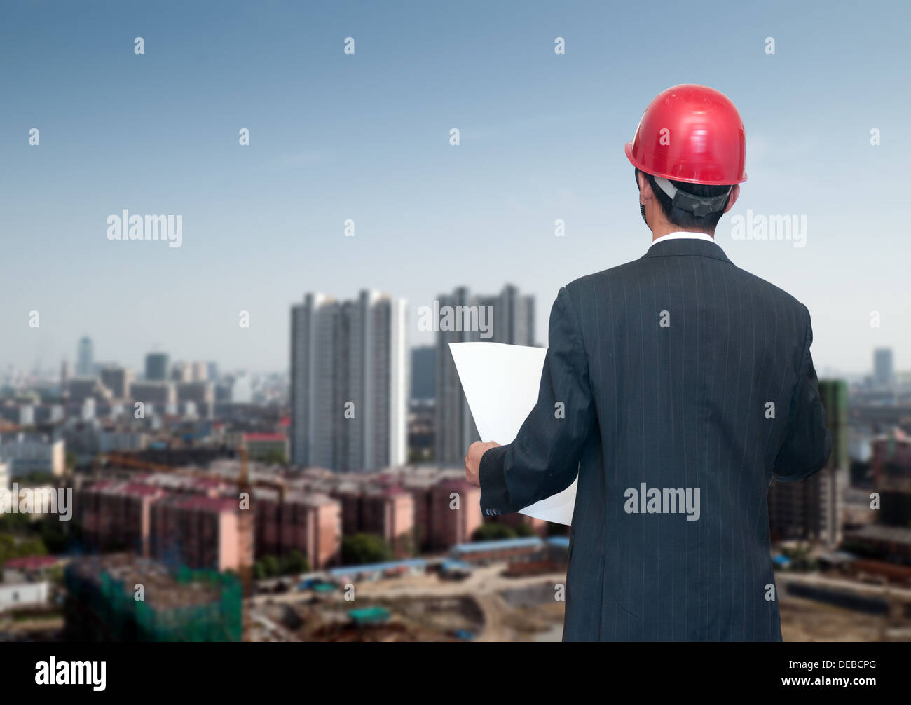 Rear view of architect looking comparing housing project with building ...