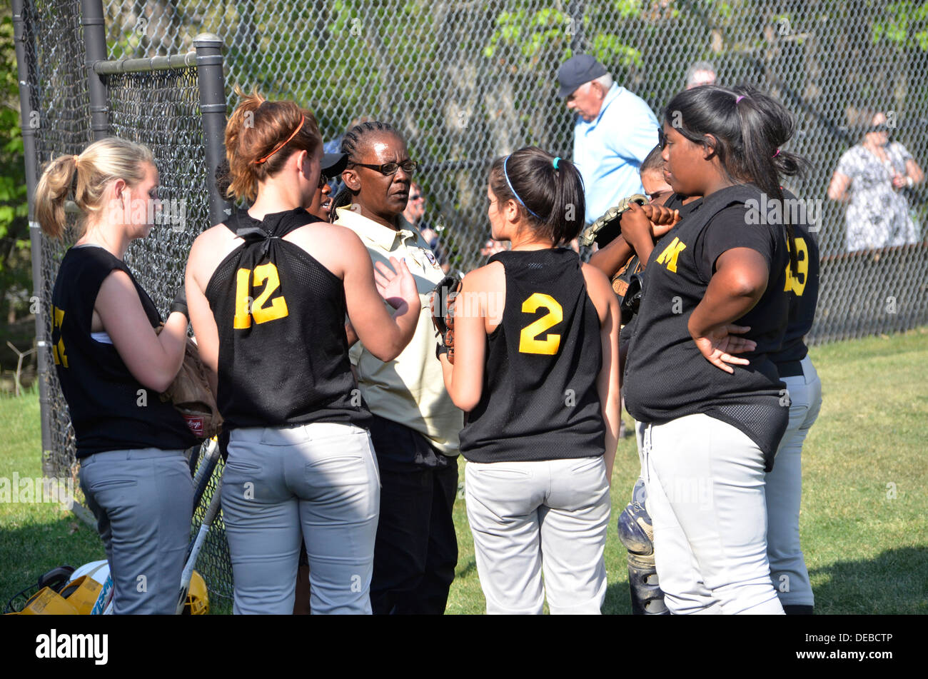 coach discusses strategy with her team at a high school softball game ...