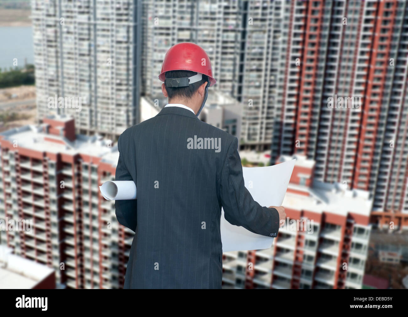 Rear view of architect looking comparing housing project with building ...
