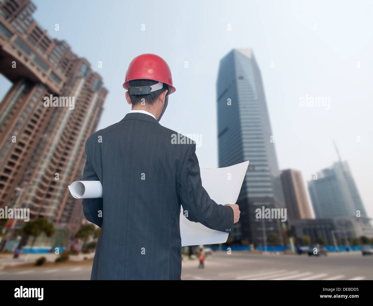 Rear view of architect looking comparing housing project with building ...