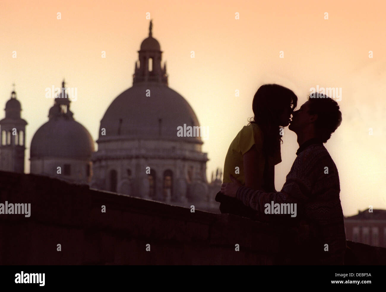 Two young lovers silhouetted against the historic background of Venice ...