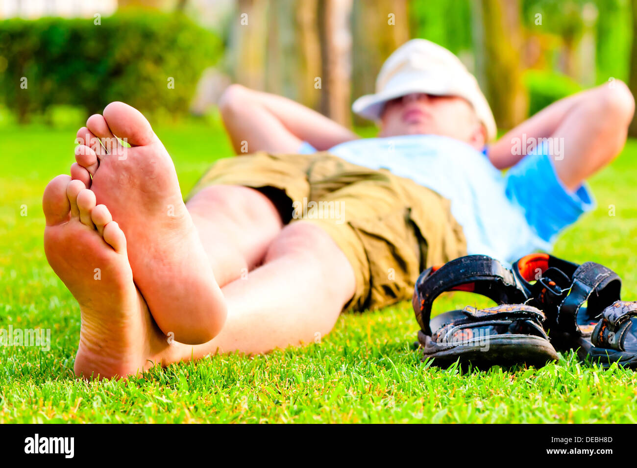barefoot man is resting on the green grass Stock Photo - Alamy