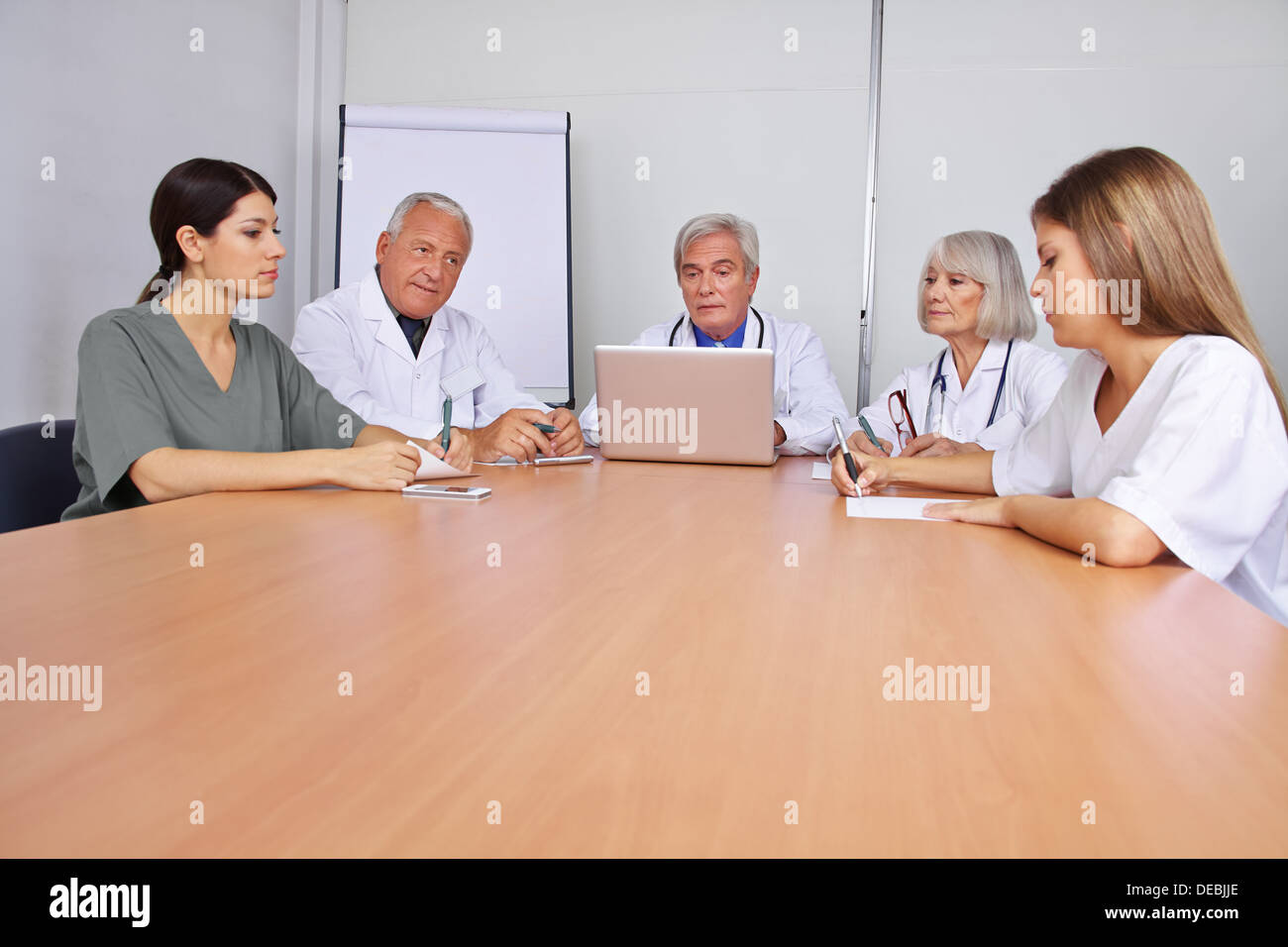 Many doctors sitting in a team meeting on a round table Stock Photo - Alamy