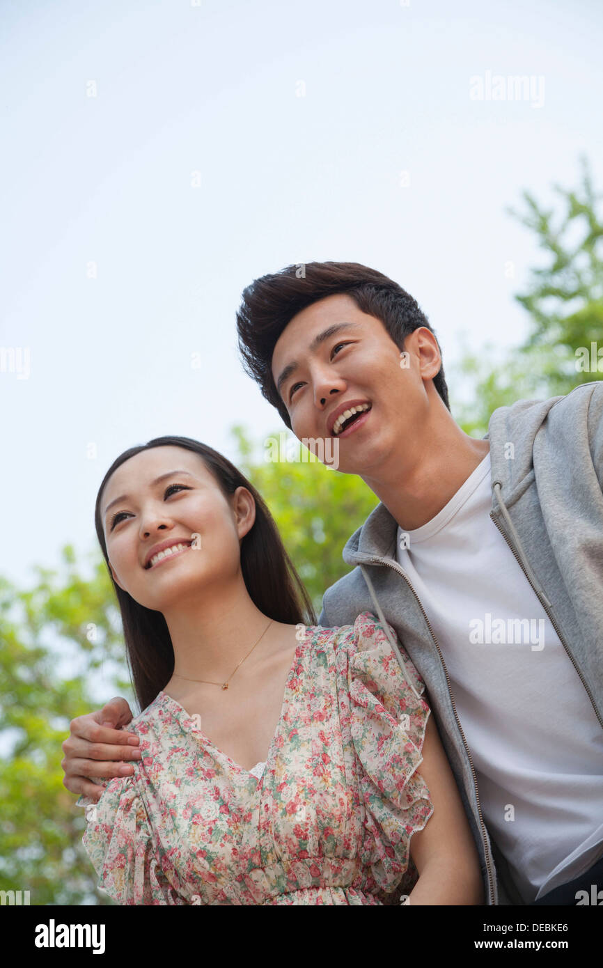 Smiling happy young couple with arm around the shoulders outdoors in a ...
