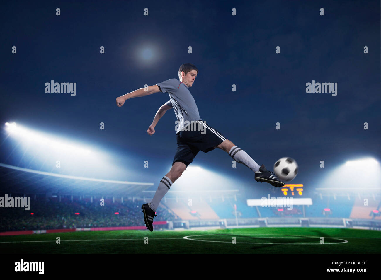 Soccer player in mid air kicking the soccer ball, stadium lights at ...