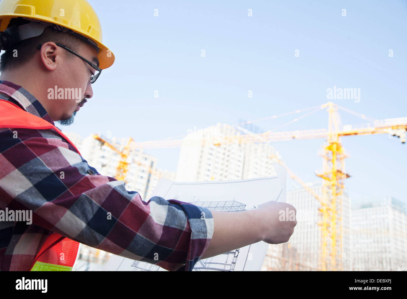 Architect looking at a blueprint outdoors at a construction site Stock ...