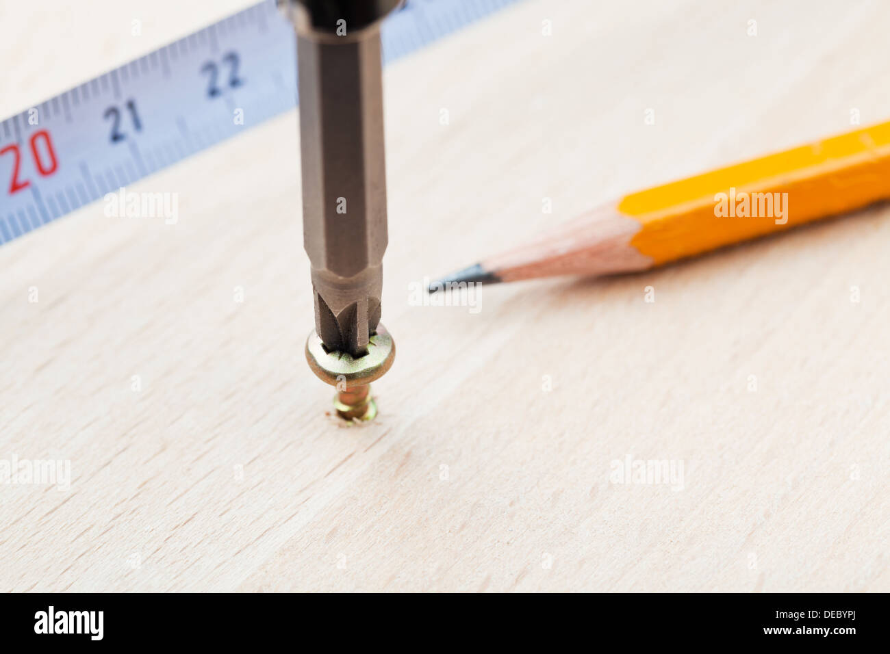 measuring tape, pencil and screwdriver wraps screw in wooden board ...