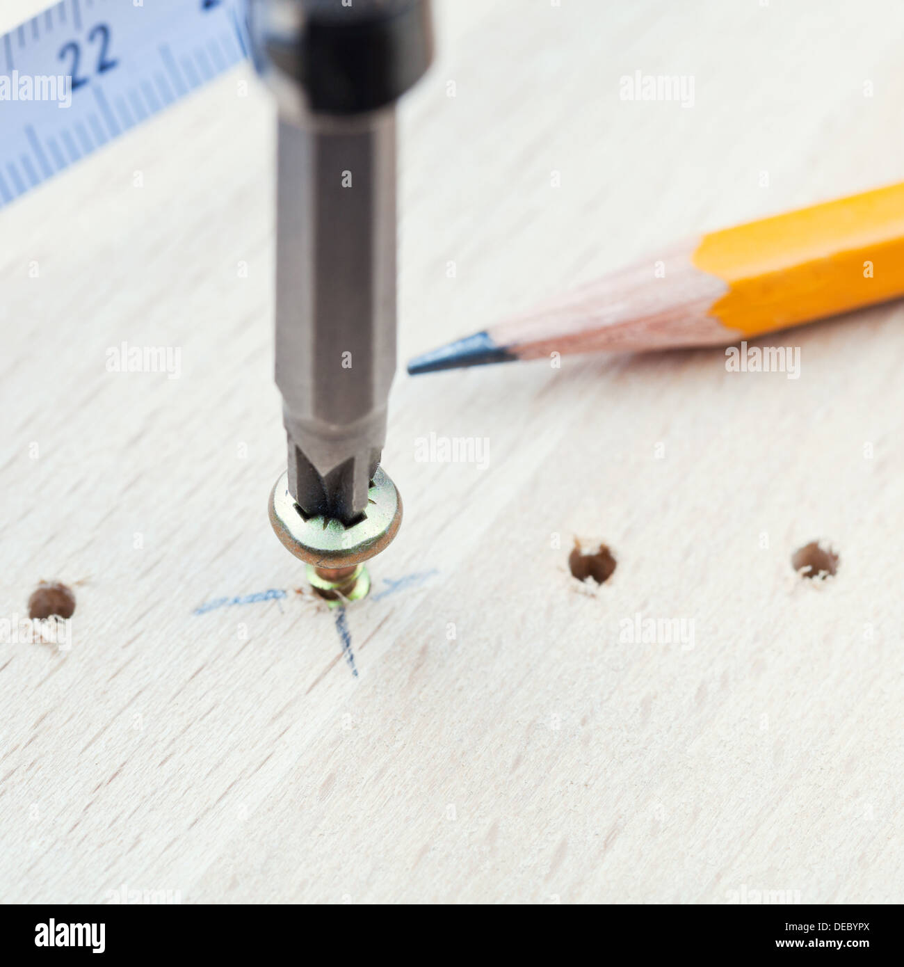 measuring tape, pencil and screwdriver wraps screw in wooden plank ...