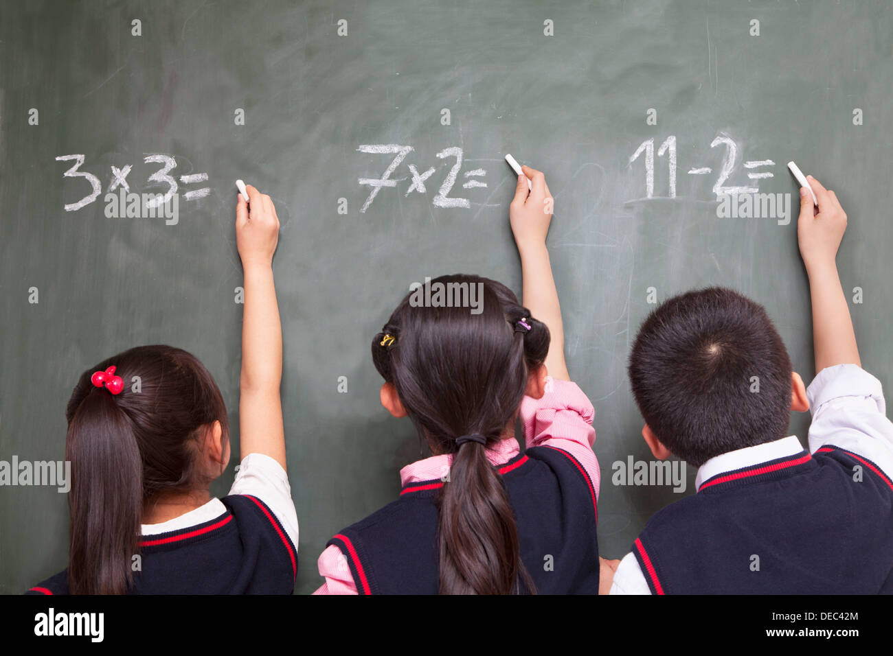 Three school children doing math equations on the blackboard Stock ...
