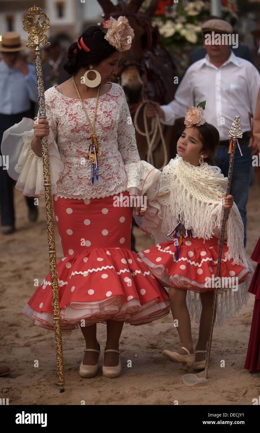 Mother and daughter, wearing the same dresses and holding staffs, speak ...