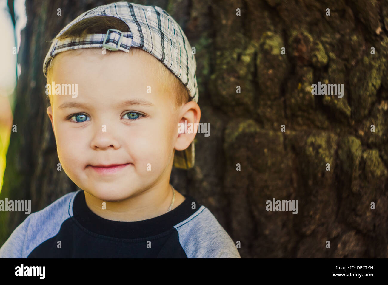 Happy caucasian child boy smiling outdoors with stripped cap, green ...