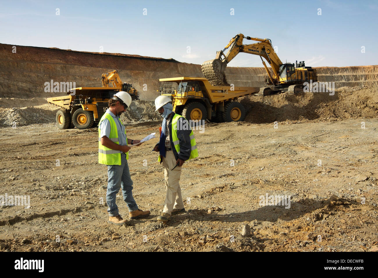 Supervisor instructing trainee in open cast surface gold mine pit with ...