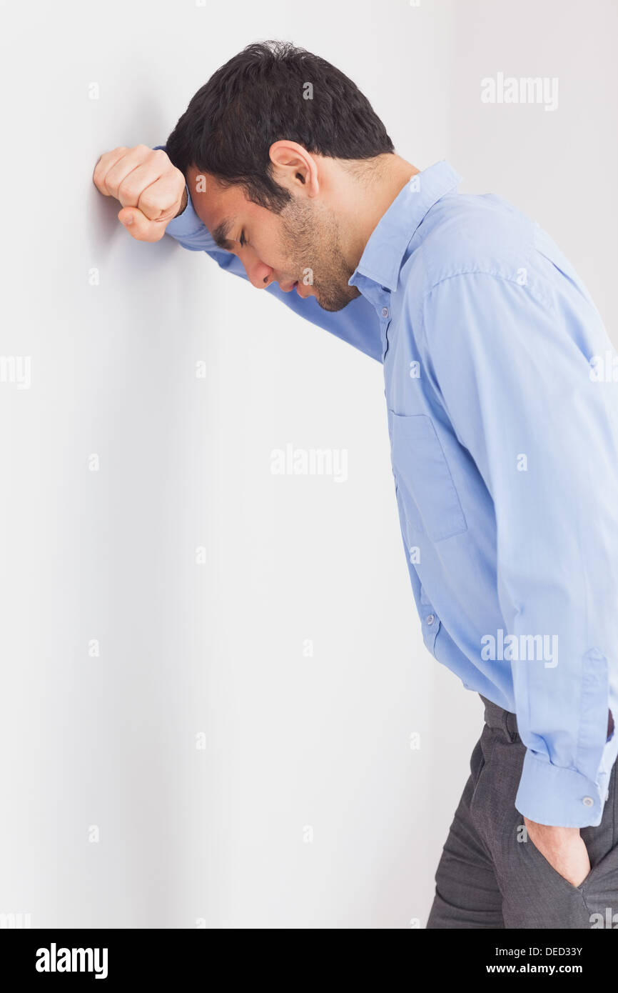 Worried man leaning his head against a wall Stock Photo - Alamy