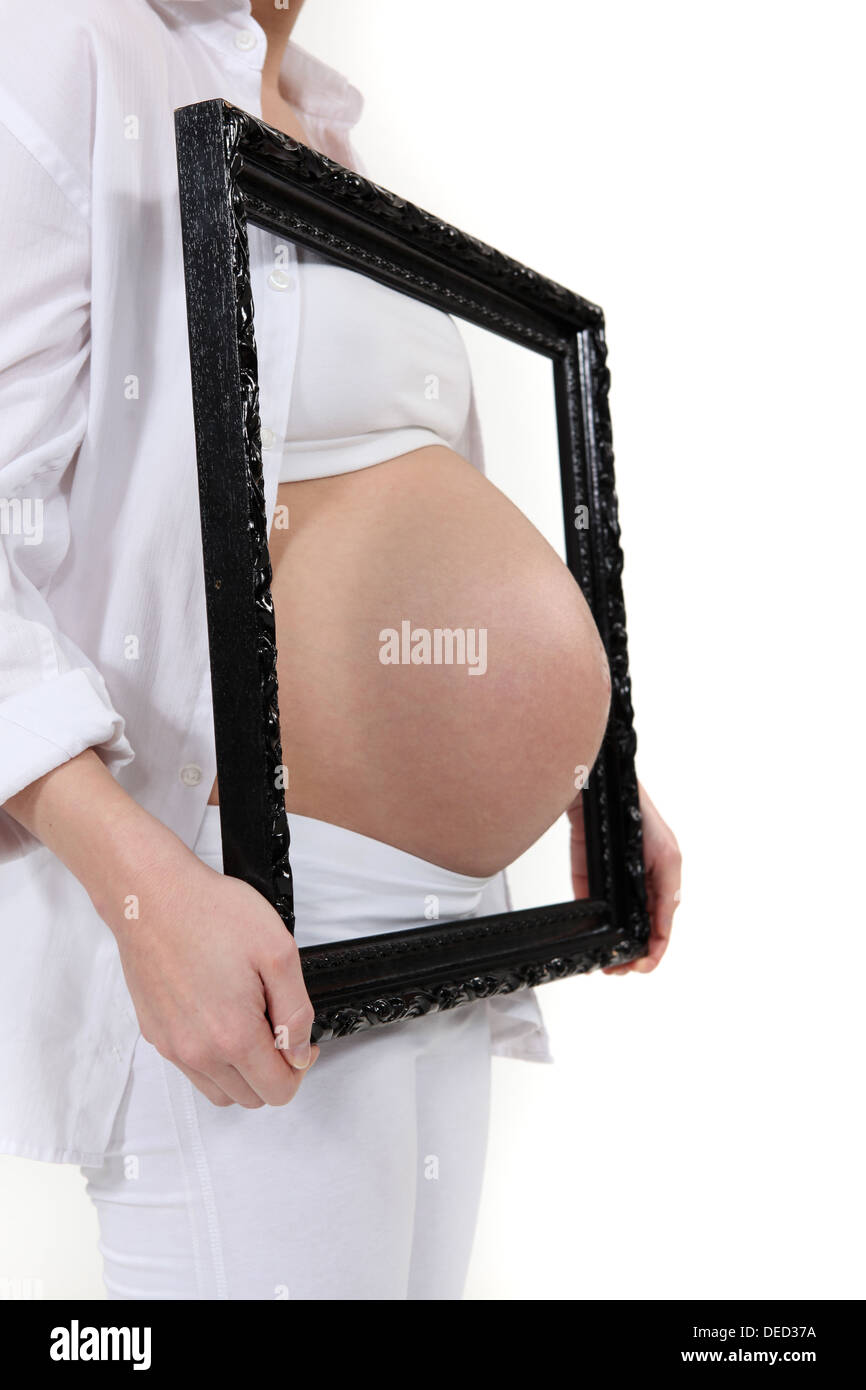 Pregnant woman poking belly through picture frame Stock Photo - Alamy