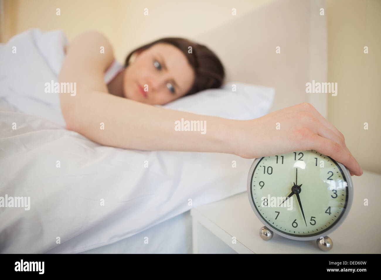 Tired girl turning off her alarm clock Stock Photo - Alamy