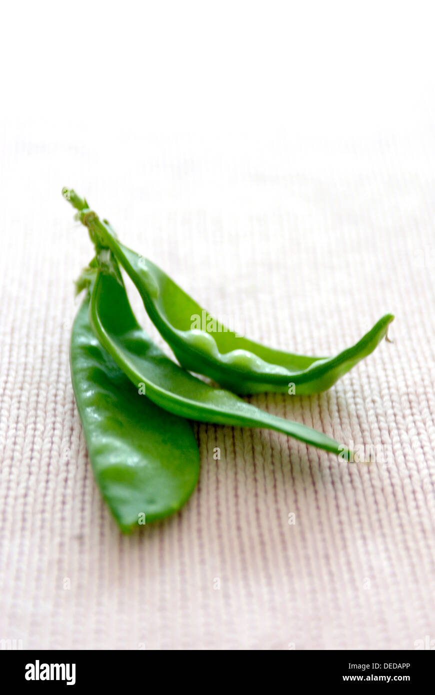 Three fresh snow pea pods on a fabric surface Stock Photo - Alamy