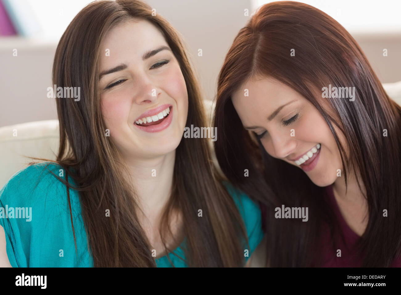 Two laughing friends sitting on the couch Stock Photo - Alamy