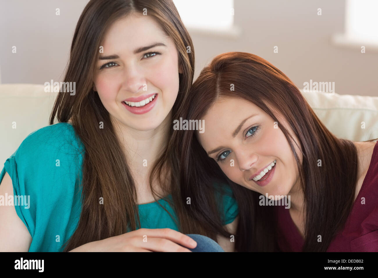 Two smiling friends sitting on the couch looking at camera Stock Photo ...
