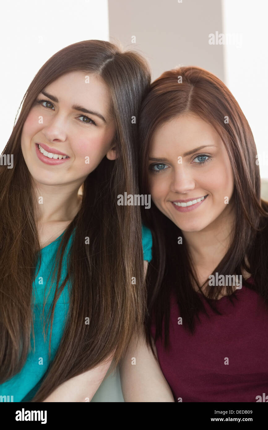 Two happy friends sitting on the couch looking at camera Stock Photo ...