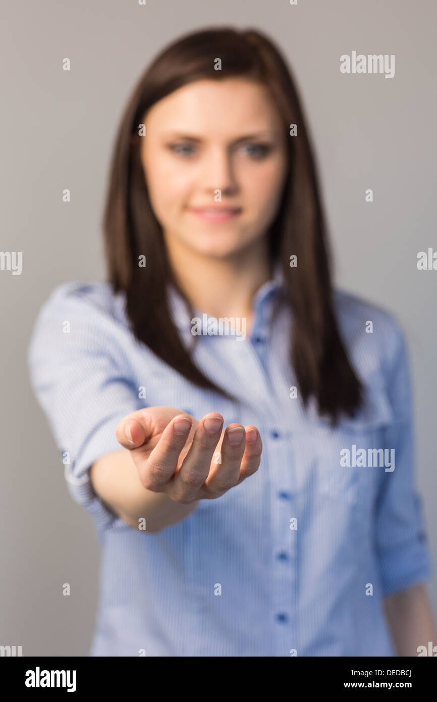 Smiling pretty brunette presenting her empty hand Stock Photo - Alamy