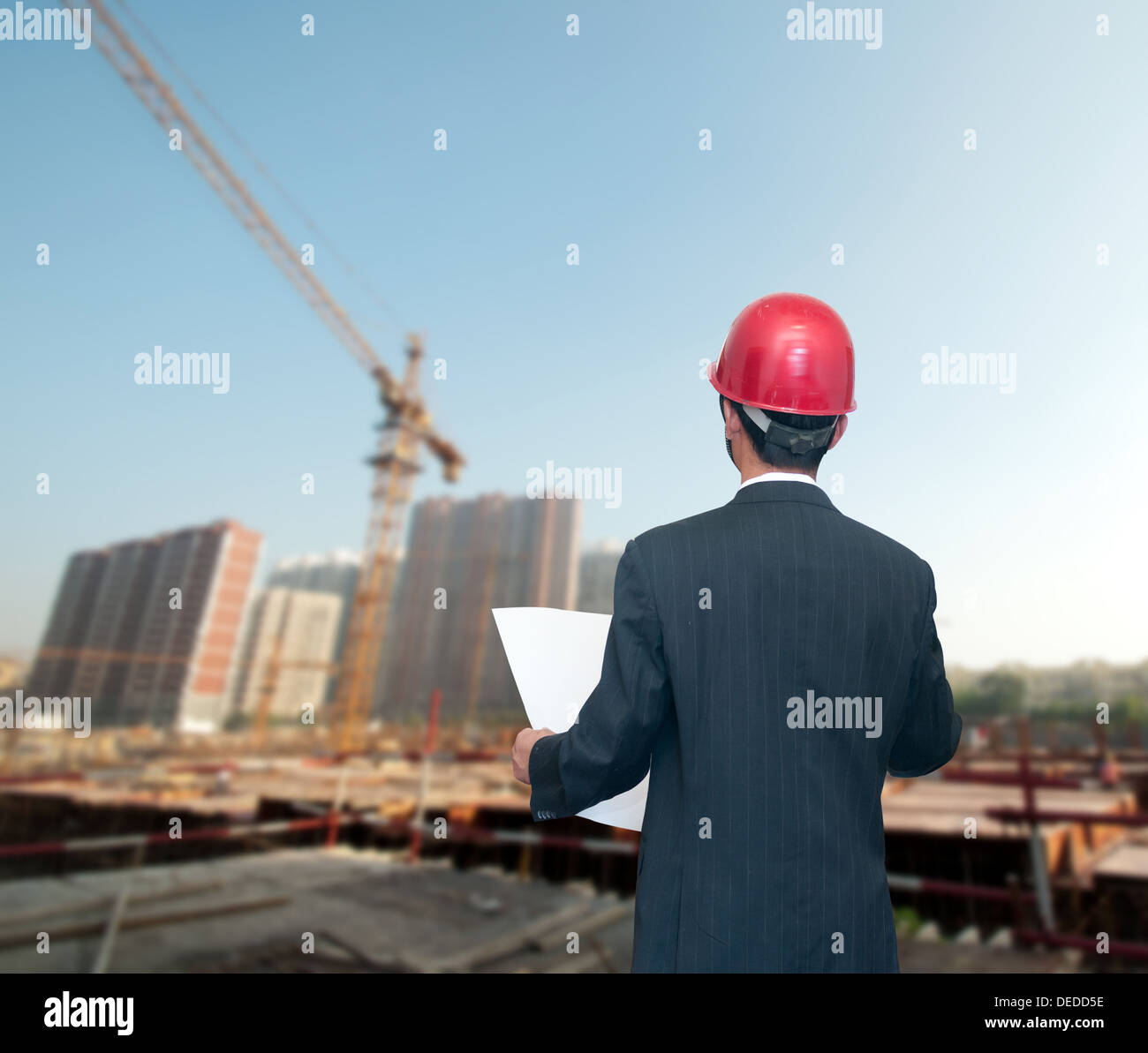 Rear view of architect looking comparing housing project with building ...